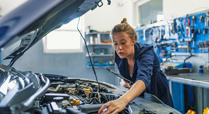 Young female mechanic checking the engine